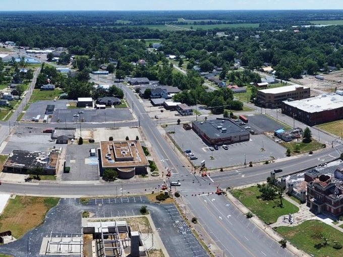 Resilience in progress! Mayfield's wide-open spaces and construction zones tell a story of rebuilding, with workers crafting tomorrow's downtown against a backdrop of steadfast forest sentinels.