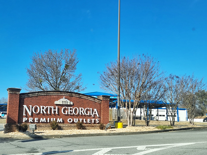 The North Georgia Premium Outlets sign sits proudly against mountain skies like a beacon for bargain hunters.
