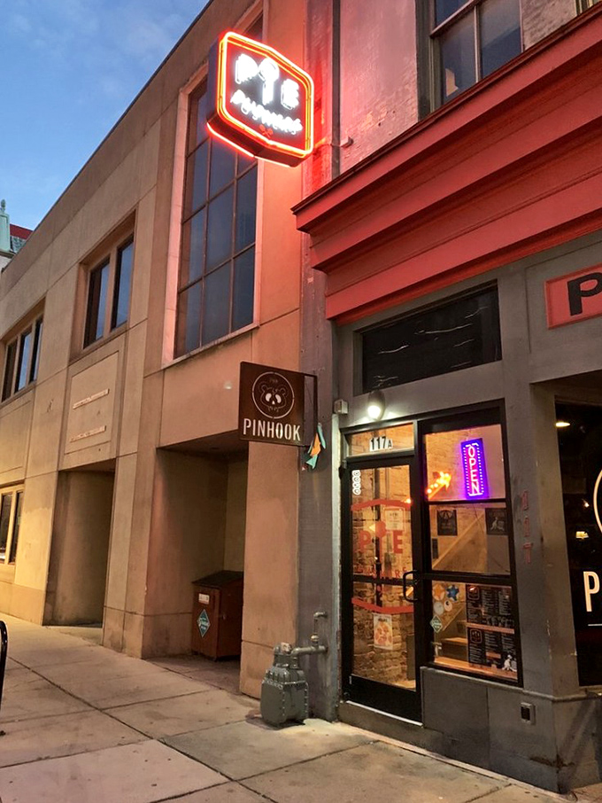 Pie Pushers' neon sign glows like a pizza lighthouse in downtown Durham. Urban vibes, unforgettable slices.