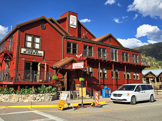 This bold red building stands proud against the mountain sky, looking like the Old West never left town.
