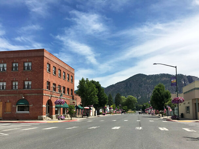 Brick buildings bathed in mountain majesty &ndash; Chewelah blooms with hanging flowers while that peak stands guard.