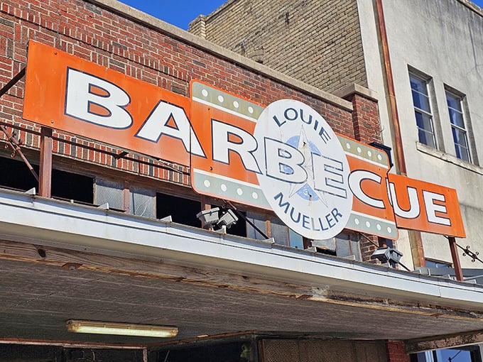 That bold orange sign is the BBQ equivalent of a lighthouse beacon. Louie Mueller's brick exterior has absorbed decades of BBQ history.