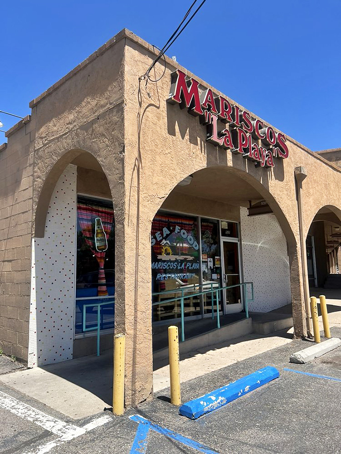 Sun-baked adobe arches guard seafood secrets at Mariscos La Playa. The blue railings hint at ocean treasures within.