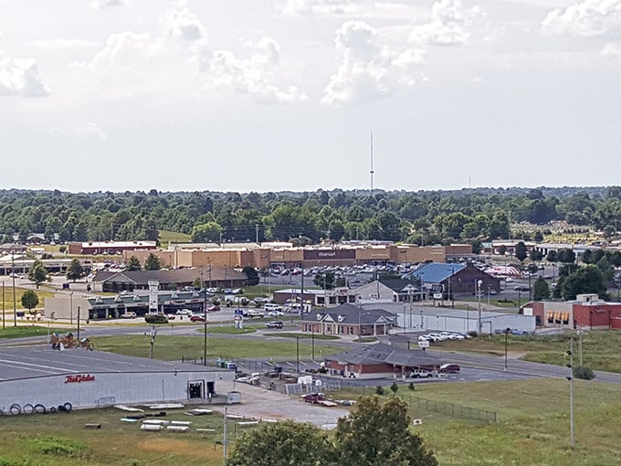Big-box charm in small-town wrapping! Mayfield's commercial district stretches beneath dramatic clouds, where Walmart meets wilderness at the edge of a tree line that seems to go on forever.