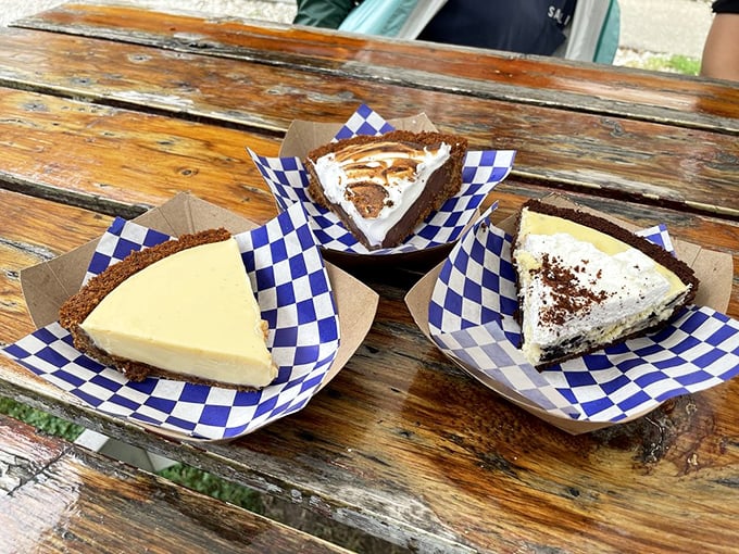 Pie trinity on blue-checkered paper &ndash; the holy communion of desserts. Each slice promises a different path to culinary enlightenment.
