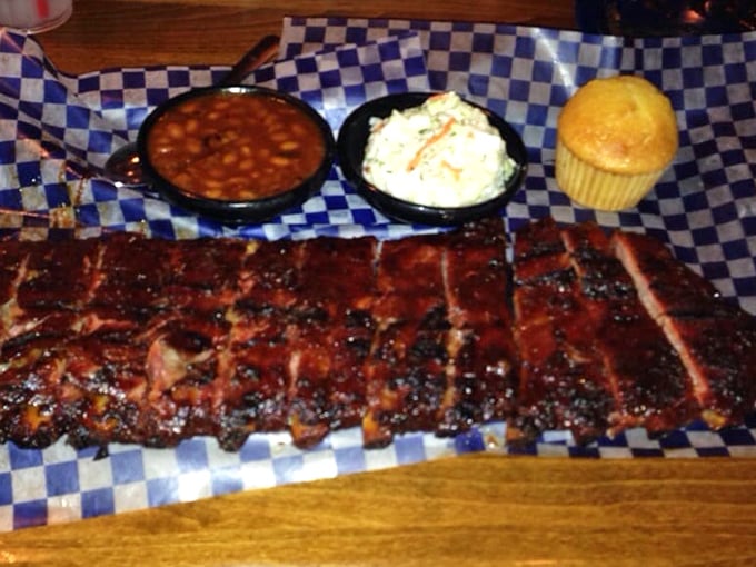 Behold the holy grail of barbecue &ndash; ribs with a perfect smoke ring, flanked by baked beans, coleslaw, and a cornbread muffin standing at attention.