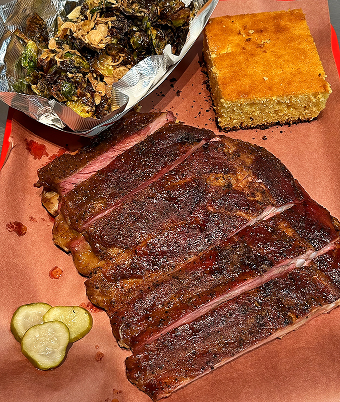 Ribs with a bark so perfect it should be in a museum, served with pickles that provide the perfect acidic counterpoint to all that smoky richness.