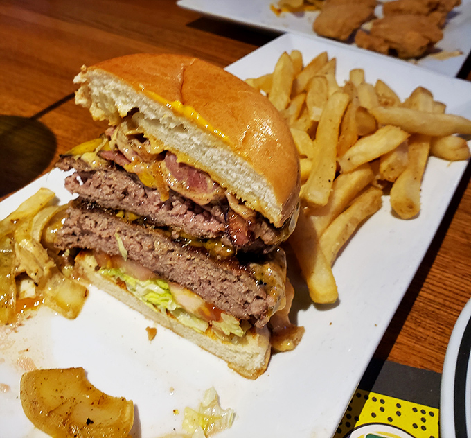This isn't just a burger—it's a towering monument to beef architecture, complete with melty cheese, crispy bacon, and a foundation of golden fries.