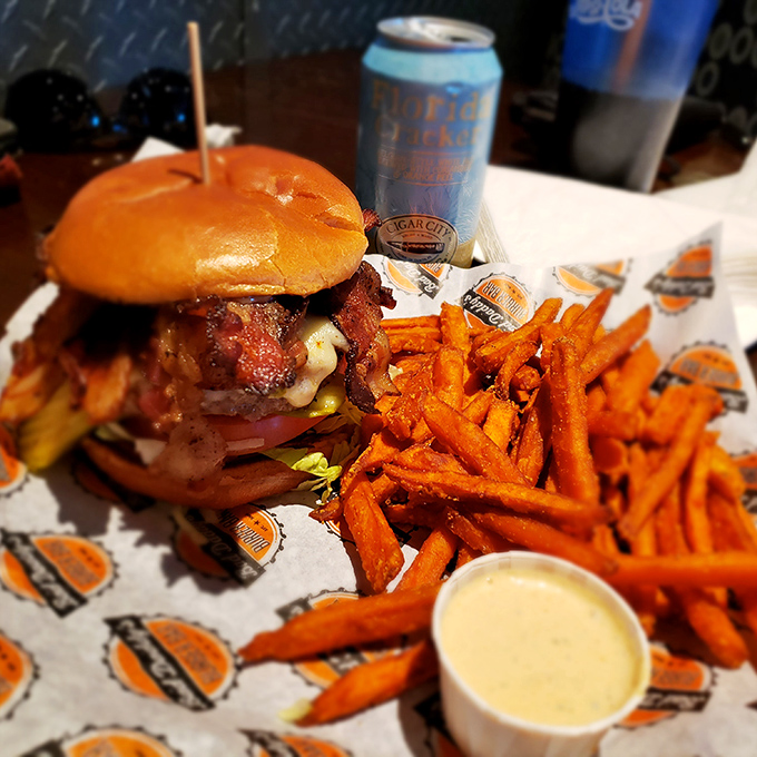 A burger architecture masterpiece that would make Frank Lloyd Wright jealous, flanked by sweet potato fries that deserve their own fan club.