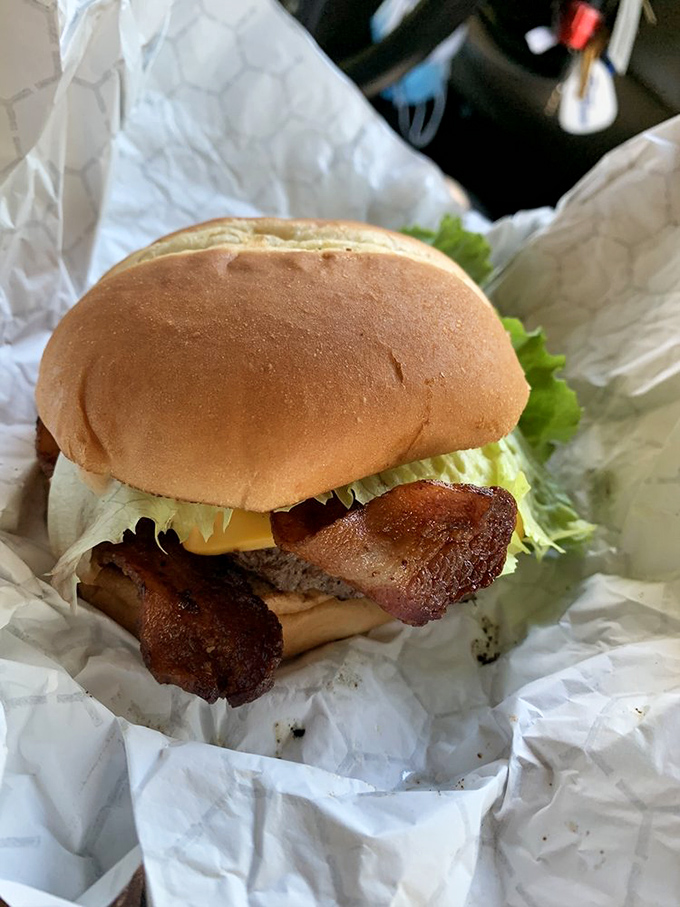 Behold the bacon cheeseburger that started it all – crispy bacon strips peeking out like a delicious secret worth sharing.