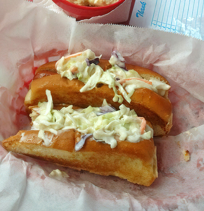 The star attraction in all its glory&mdash;a hot dog transformed into culinary poetry with creamy coleslaw piled high enough to require strategic first-bite planning.