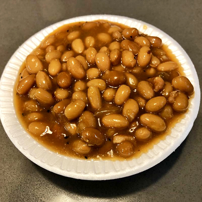 These baked beans aren't just a side dish; they're tiny legume ambassadors that have clearly spent quality time absorbing smoky wisdom from nearby pork.