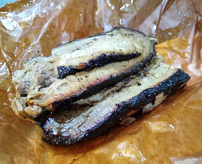 Behold the holy grail of barbecue: perfectly smoked brisket with that textbook pink smoke ring and bark that would make a Texas pitmaster weep with joy.