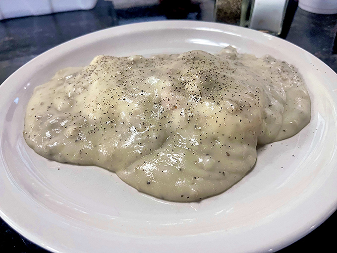 Behold the star attraction: gravy cascading over biscuits like a peppery waterfall of breakfast bliss. Diets come here to die happy.