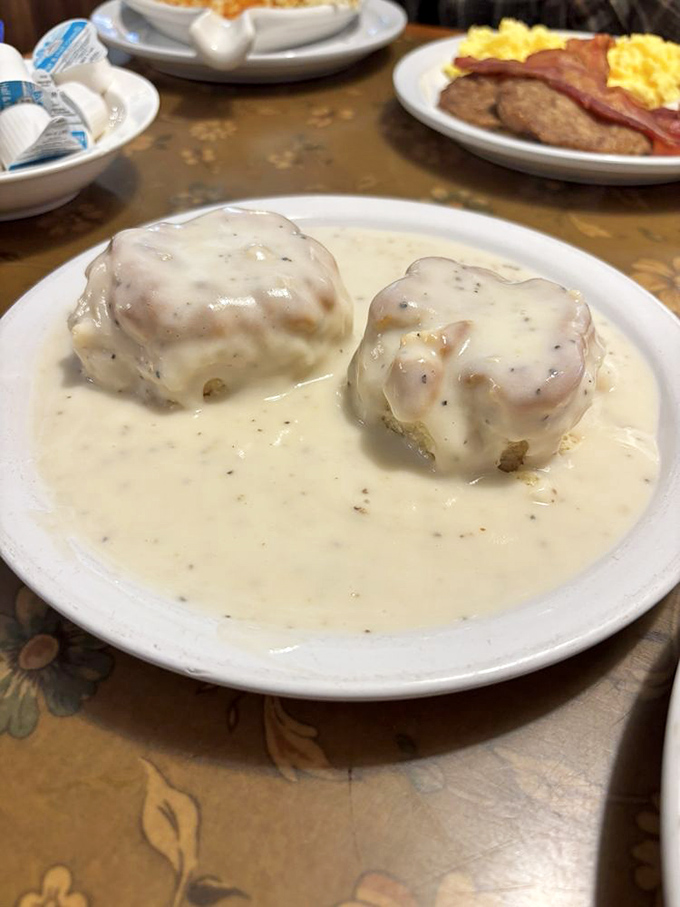 Behold the star attraction: biscuits drowning in creamy, pepper-flecked gravy. Two golden islands in a sea of savory perfection that might just change your life.