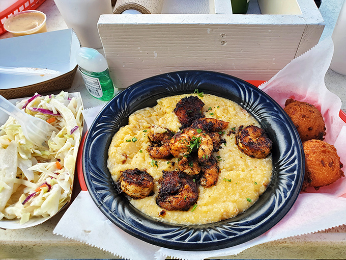 Blackened shrimp nestled on creamy grits with hushpuppies standing by. Southern comfort food that makes you want to hug the chef.