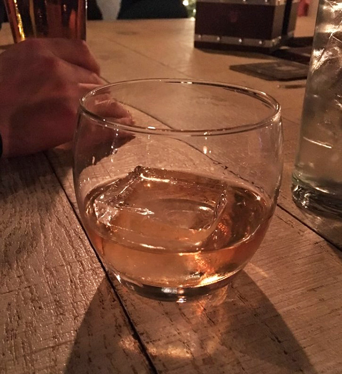 Bourbon in its natural habitat – amber perfection catching the light on weathered wood, just waiting to tell you its story.