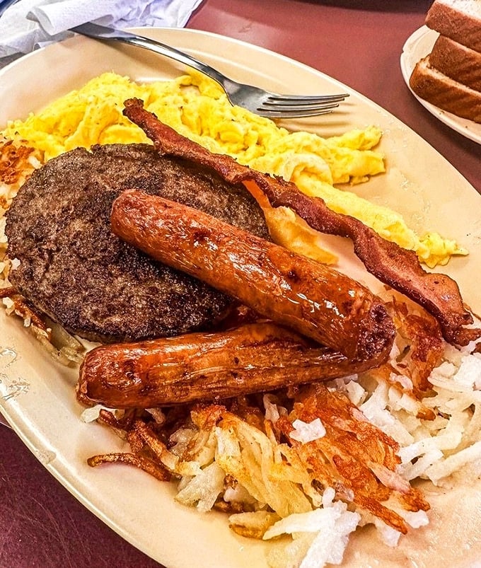 Breakfast nirvana achieved: golden hash browns, perfectly scrambled eggs, sausage links glistening with promise, and a burger patty because why not?