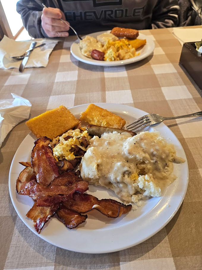 Breakfast nirvana: crispy bacon, fluffy eggs, and biscuits smothered in creamy gravy. The checkered tablecloth is practically mandatory for this level of comfort.