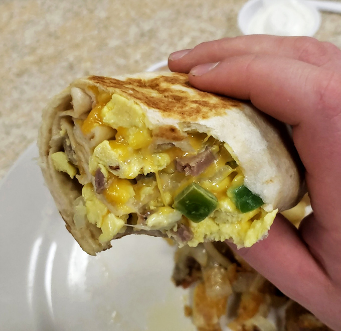 Behold the legendary breakfast burrito in mid-bite glory&mdash;eggs, peppers, cheese, and meat wrapped in a perfectly griddled tortilla that's worth setting your alarm for.