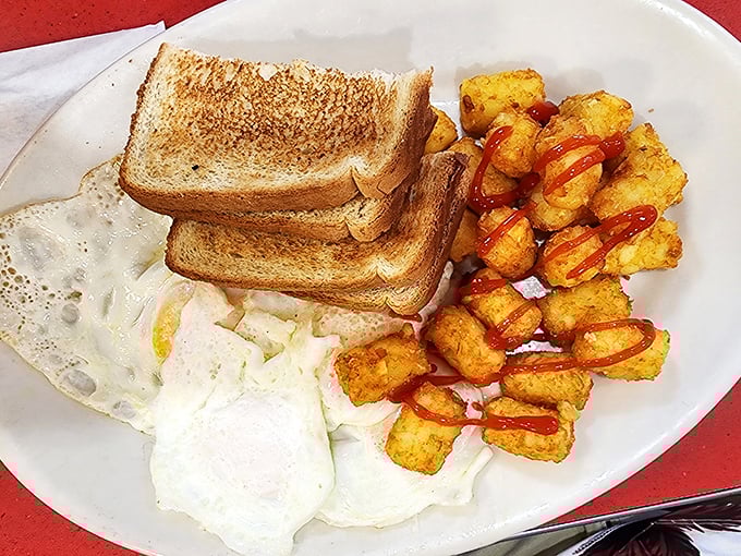 Breakfast perfection on a plate: golden toast, perfectly cooked eggs, and those tater tots with a drizzle of ketchup&mdash;proof that sometimes the simplest meals bring the greatest joy.