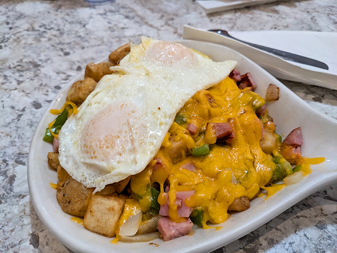 Breakfast architecture at its finest&mdash;crispy potatoes supporting a melty cheese roof, with ham and peppers playing structural support beneath sunny-side-up skylights.