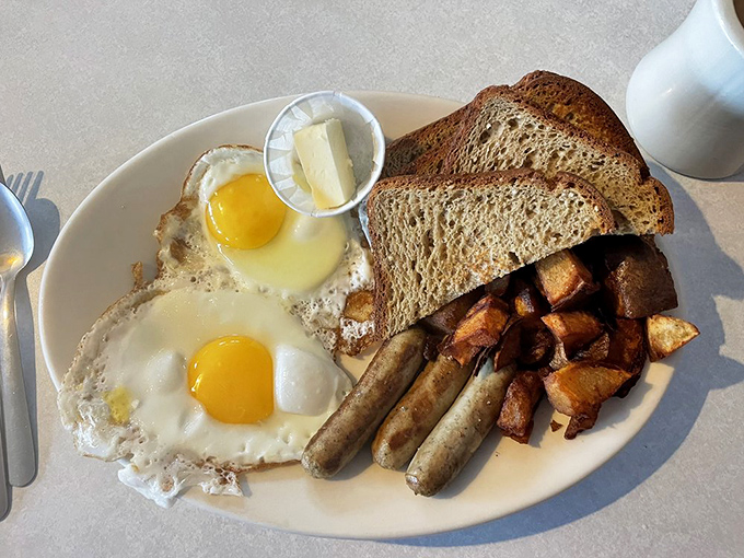 Two sunny-side-up eggs, perfectly browned home fries, and sausage links&mdash;the breakfast trinity that proves simplicity is the ultimate sophistication.