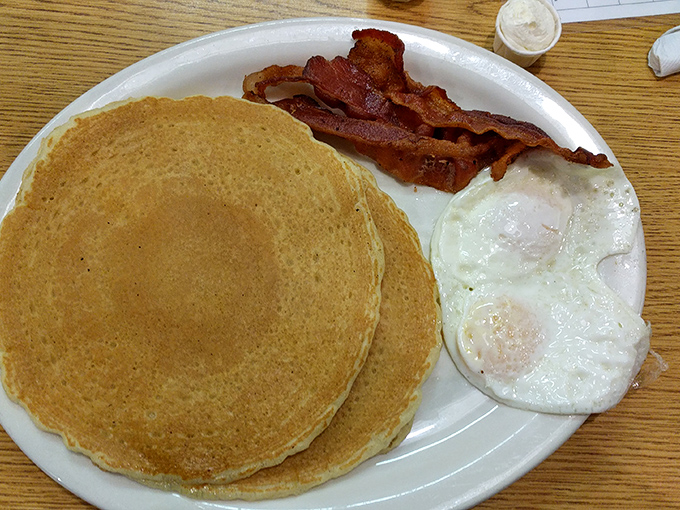 Behold the holy trinity of breakfast perfection: golden pancakes with edges crisp enough to make you weep, bacon with the ideal bend, and eggs sunny enough to brighten your day.