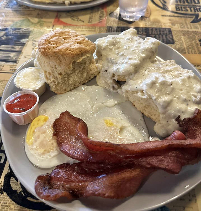 Biscuits smothered in creamy gravy alongside perfectly cooked eggs and bacon—comfort food that speaks the universal language of "good morning."