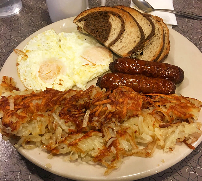 Breakfast perfection on a plate: crispy hash browns with the golden-brown edge that dreams are made of, alongside eggs and sausage.