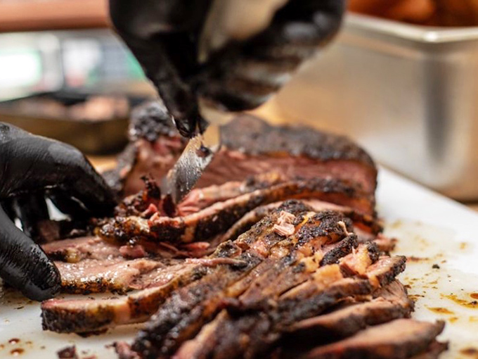 Behold the brisket, sliced with surgical precision, revealing that perfect pink smoke ring that makes barbecue lovers weak at the knees.