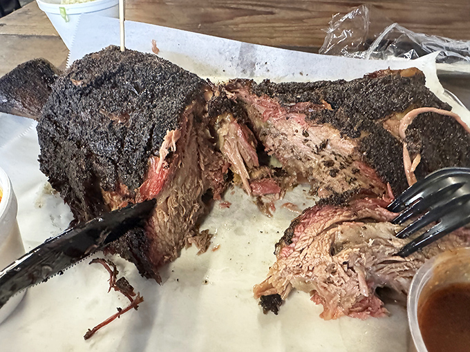 Behold the brisket in all its pepper-crusted glory, that telltale smoke ring announcing to your eyes what your nose already knew: perfection takes patience.