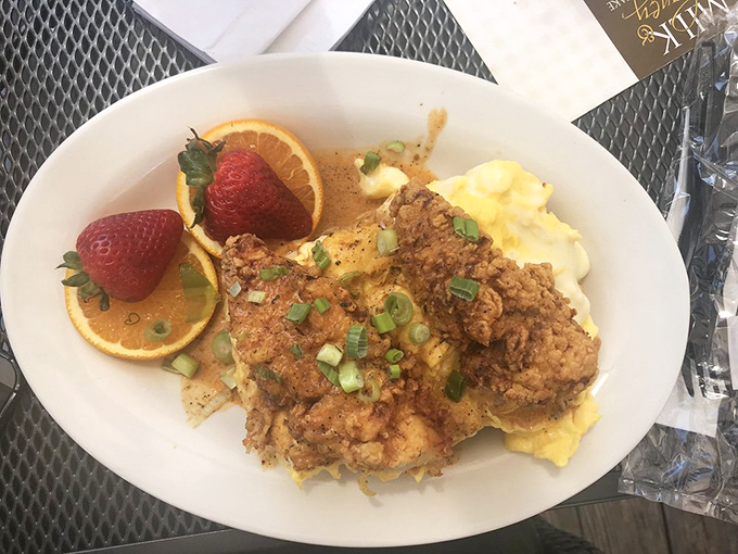 Crispy fried chicken nestled against fluffy scrambled eggs, with fresh fruit providing that "yes, this is technically a balanced meal" alibi.