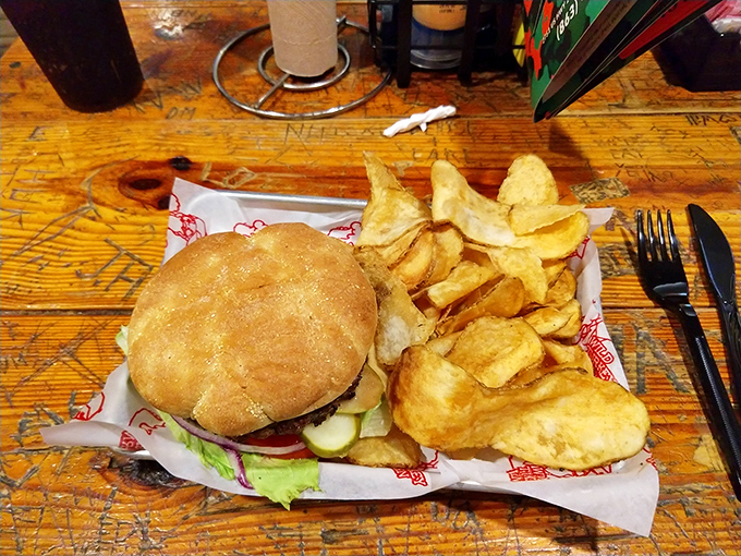 Simplicity at its finest: a perfectly assembled burger with house-made chips. The scratched wooden table tells stories of thousands of satisfied diners before you.