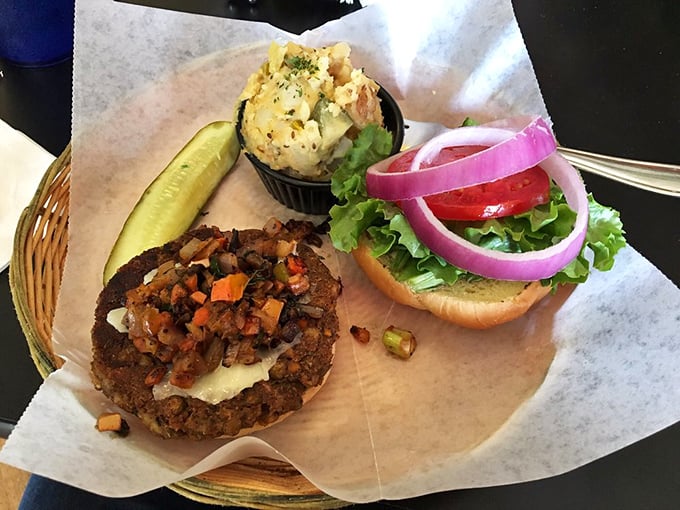 This isn't just a burger; it's a hand-formed manifesto of local flavors topped with colorful vegetables and served with a side of potato salad perfection.