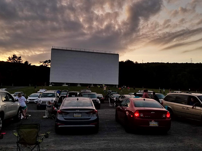 Cars line up like eager moviegoers themselves, headlights dimmed, as the American flag proudly introduces the evening's entertainment.