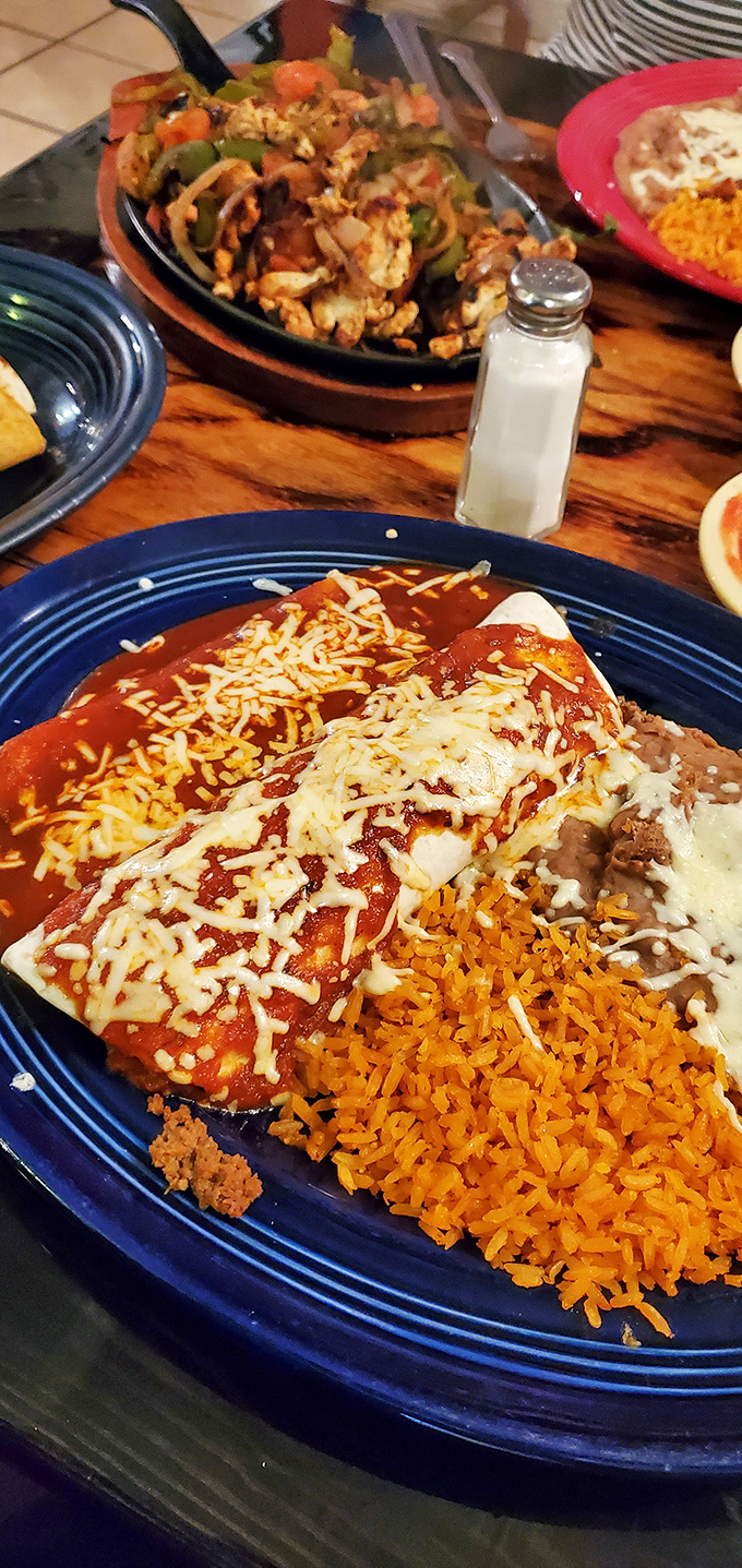Behold, the star of our show! Enchiladas bathed in that brick-red sauce with perfectly melted cheese and golden rice. Your diet called—it's taking the day off.