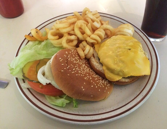 The star of the show arrives: a perfectly melted cheeseburger with curly fries that makes you wonder why anyone bothered inventing molecular gastronomy.