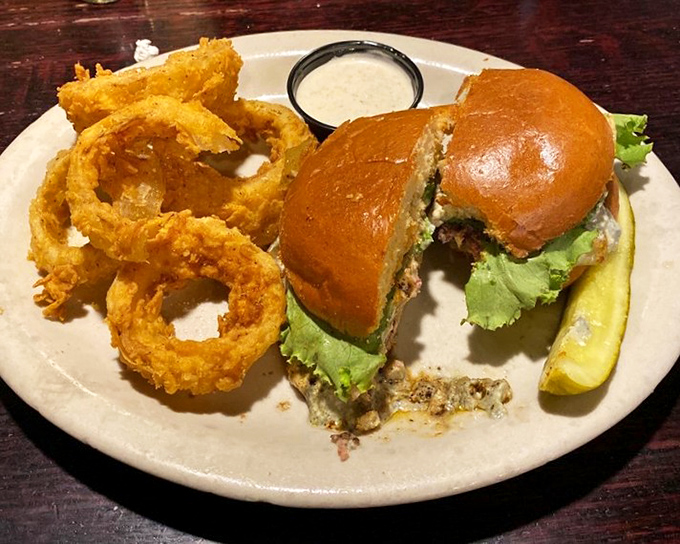 A burger so perfectly constructed it deserves its own architectural award, complete with golden onion rings that could double as halos.