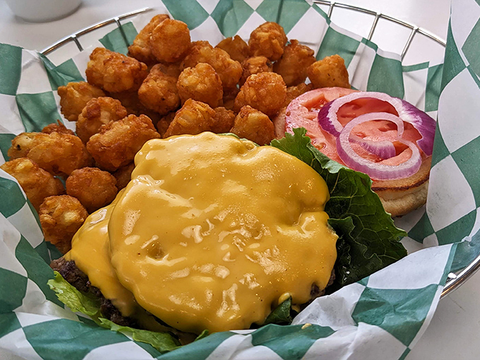 This isn't just a cheeseburger; it's edible architecture &ndash; a golden cheese blanket cascading over a perfectly seared patty alongside crispy tater tots.