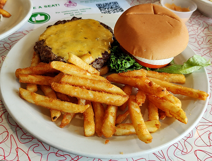 Behold the star attraction: a perfectly grilled cheeseburger with golden fries that would make any road trip worthwhile.