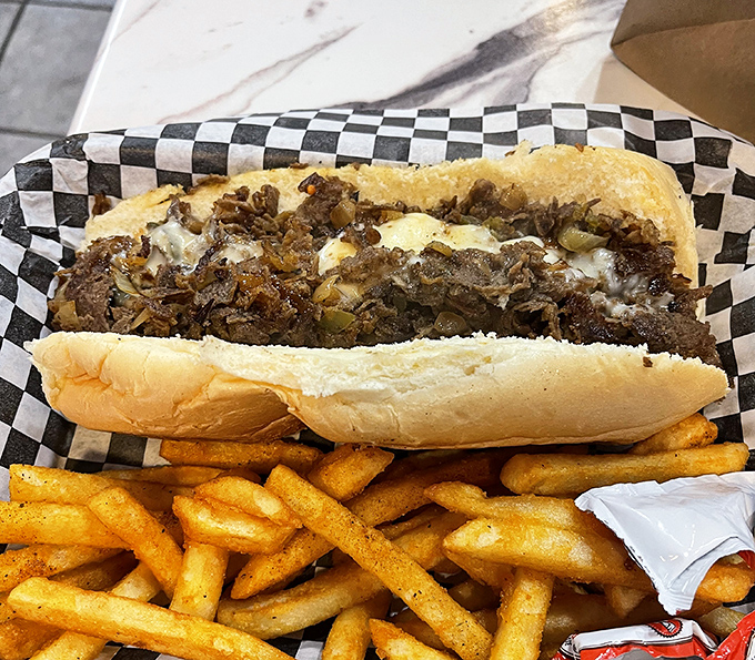 Behold the holy grail of cheesesteaks &ndash; thinly sliced ribeye, perfectly caramelized onions, and melted cheese nestled in that ideal roll, with golden fries standing guard.
