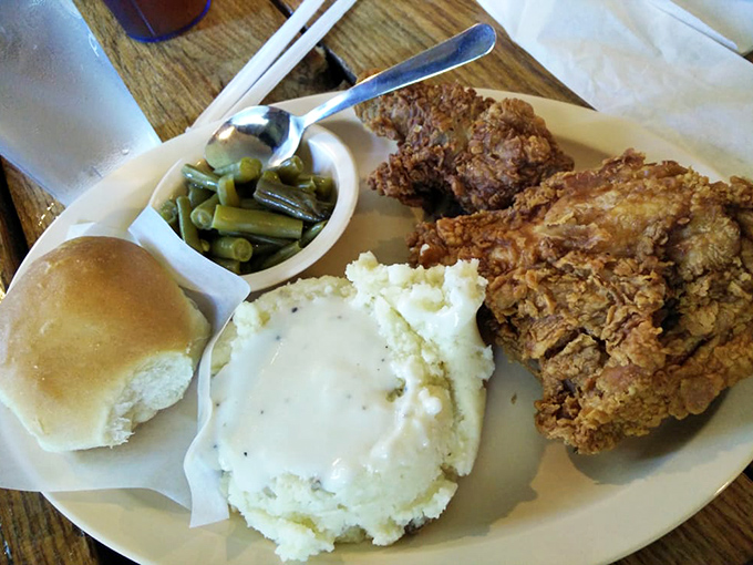 Golden-crusted fried chicken that crackles with each bite, nestled alongside cloud-like mashed potatoes and green beans that clearly know a ham hock personally. 
