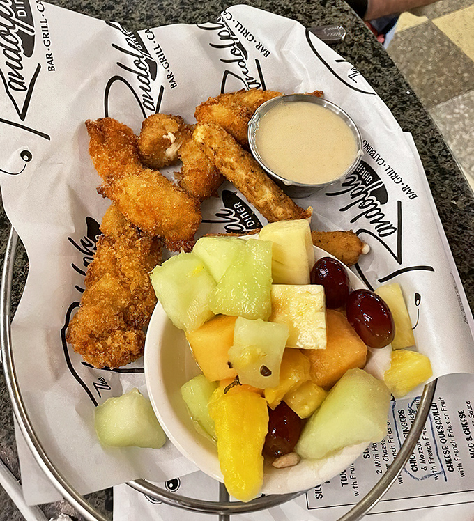 Golden-brown chicken fingers that demand a moment of silence with each bite, served with fresh fruit that almost makes it healthy.