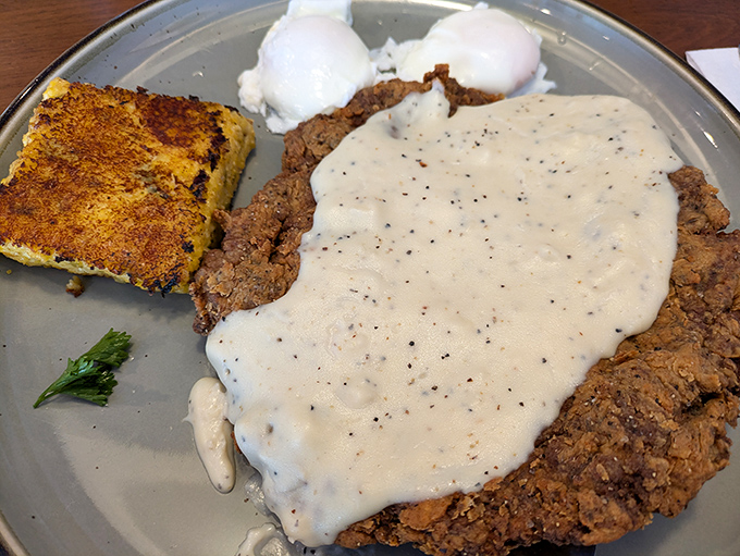 Behold the star attraction: chicken fried steak wearing its pepper-flecked gravy like a royal robe, with poached eggs standing guard.
