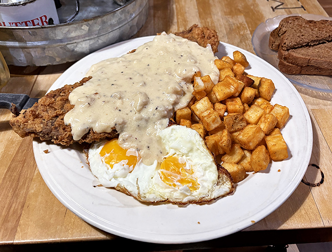 Behold the holy trinity of comfort food: chicken fried steak smothered in peppery gravy, golden home fries, and sunny-side-up eggs that wink at you from the plate.