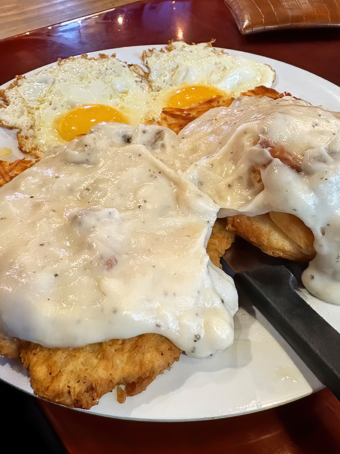 Behold the star of the show! Chicken fried steak smothered in peppery gravy with sunny-side-up eggs &ndash; breakfast nirvana on a plate.