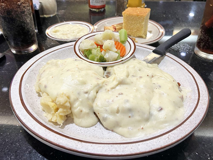 Behold the star attraction: chicken fried steak smothered in peppery gravy that cascades over fluffy mashed potatoes like a savory waterfall.