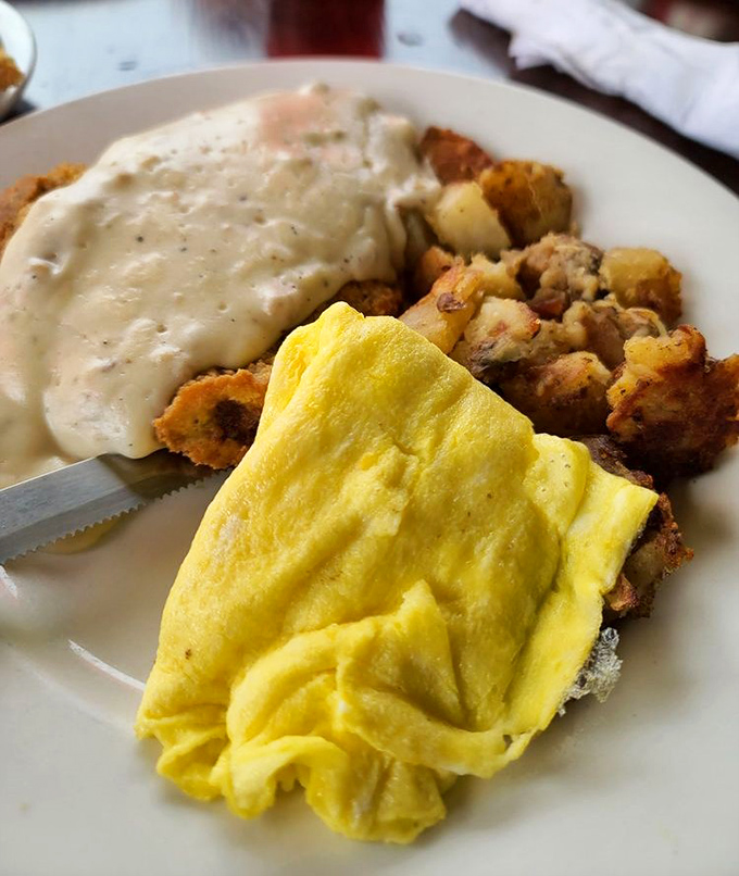 Behold the star attraction: chicken fried steak smothered in pepper gravy alongside fluffy eggs and crispy potatoes – a holy trinity of breakfast perfection.