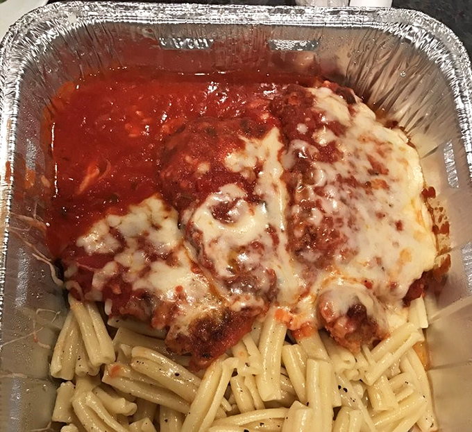 Behold the chicken parmesan in its natural habitat: a to-go container that can barely contain all that cheesy, saucy glory.